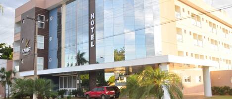 Um hotel moderno com fachada curva, grandes janelas de vidro e um letreiro chamativo com a palavra 'HOTEL'.