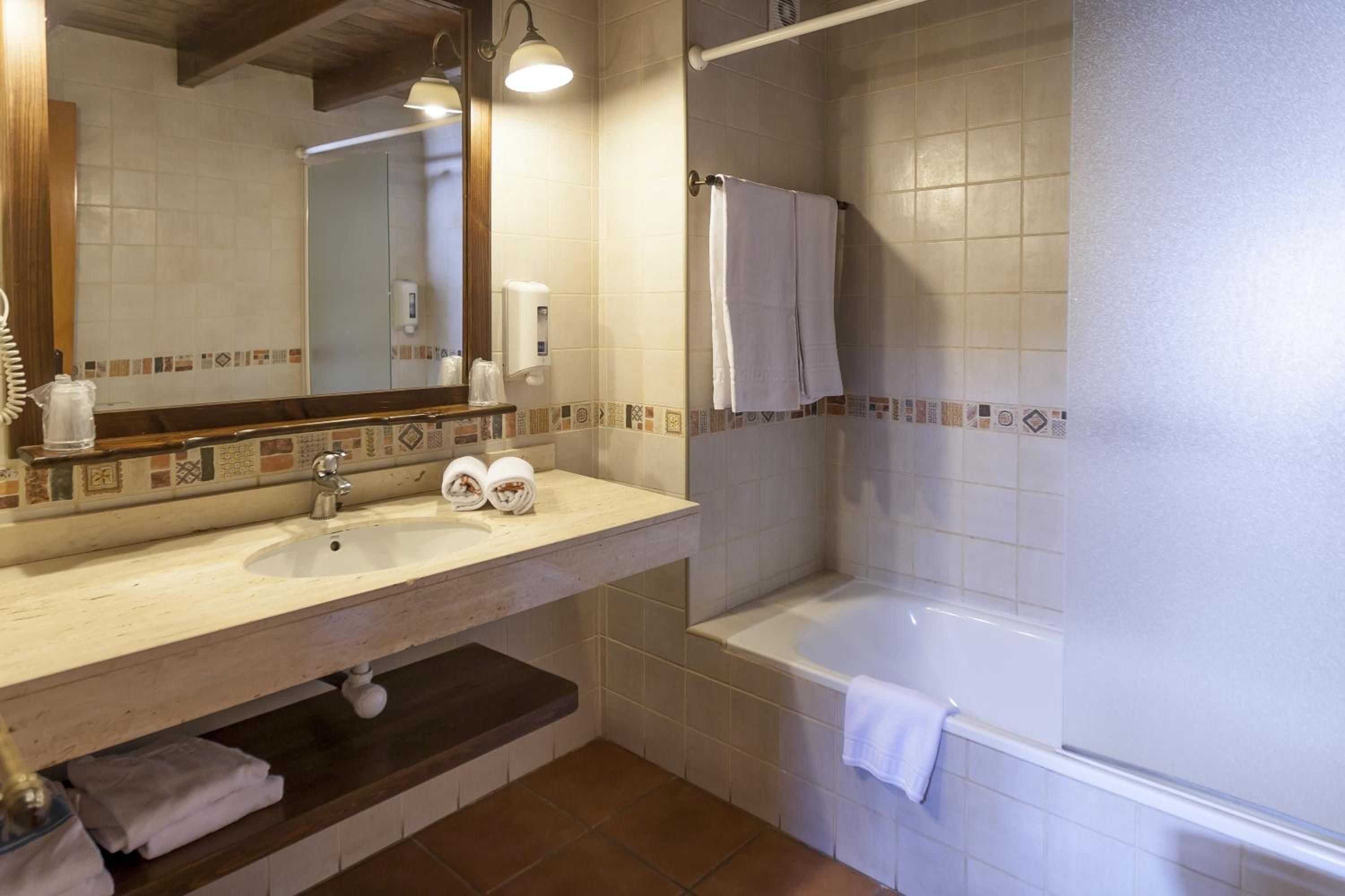Casa de banho com lavatório, espelho, porta-toalhas e banheira.