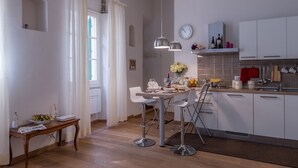 Cozinha moderna com armários brancos, sala de jantar com mesa e cadeiras, e um pequeno espaço bar com pia e utensílios.
