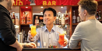 Uma área de bar com um bartender servindo bebidas aos clientes.