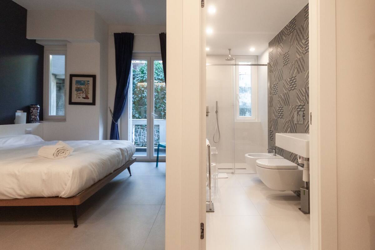 Quarto com cama e banheiro com chuveiro e vaso sanitário.