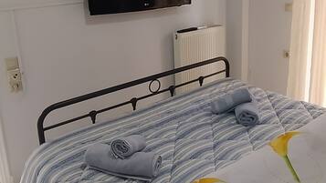 Quarto com cama, televisão montada e ar condicionado.