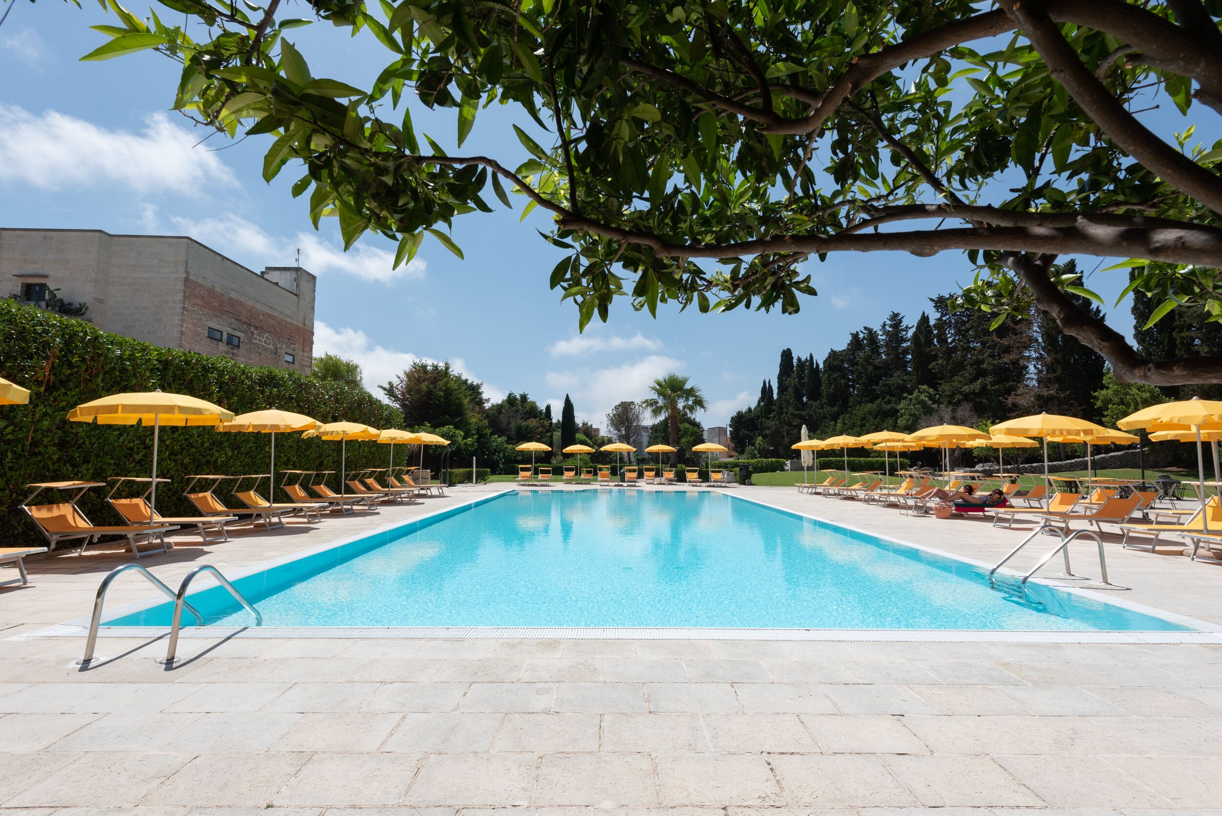 Piscina com guarda-sóis e espreguiçadeiras.