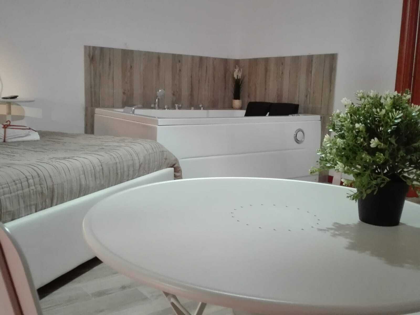 Quarto com cama, mesa de cabeceira, cômoda e planta em vaso.