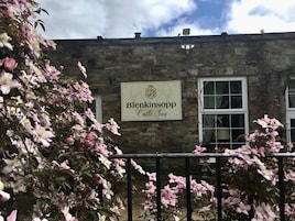 Um edifício de pedra com uma placa que diz 'Blenkinsopp Castle Inn'.