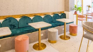 Um lobby moderno de hotel com área de estar, sofás verde-água e detalhes dourados.