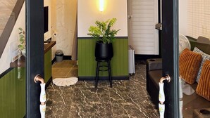 Um interior moderno com piso de mármore, detalhes em verde, uma planta em vaso e uma escada.
