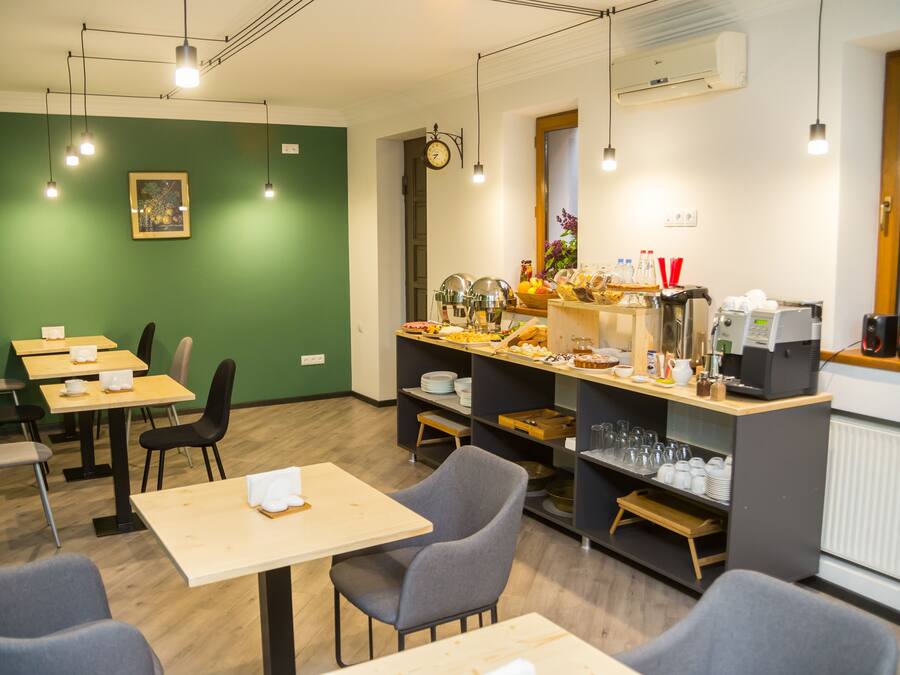 Um café com mesas e cadeiras, um balcão com comida e bebidas, e um relógio na parede.