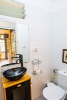 Casa de banho compacta com lavatório preto, sanita e espelho.