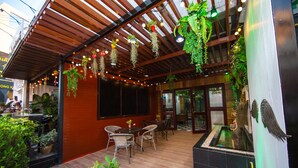 Um pátio externo com piso de madeira, plantas pendentes e mobiliário para área externa.