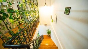 Escada com guarda-corrimão de metal e parede verde com plantas de um lado.