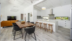 Uma cozinha moderna com armários brancos, uma ilha grande e um fogão embutido.