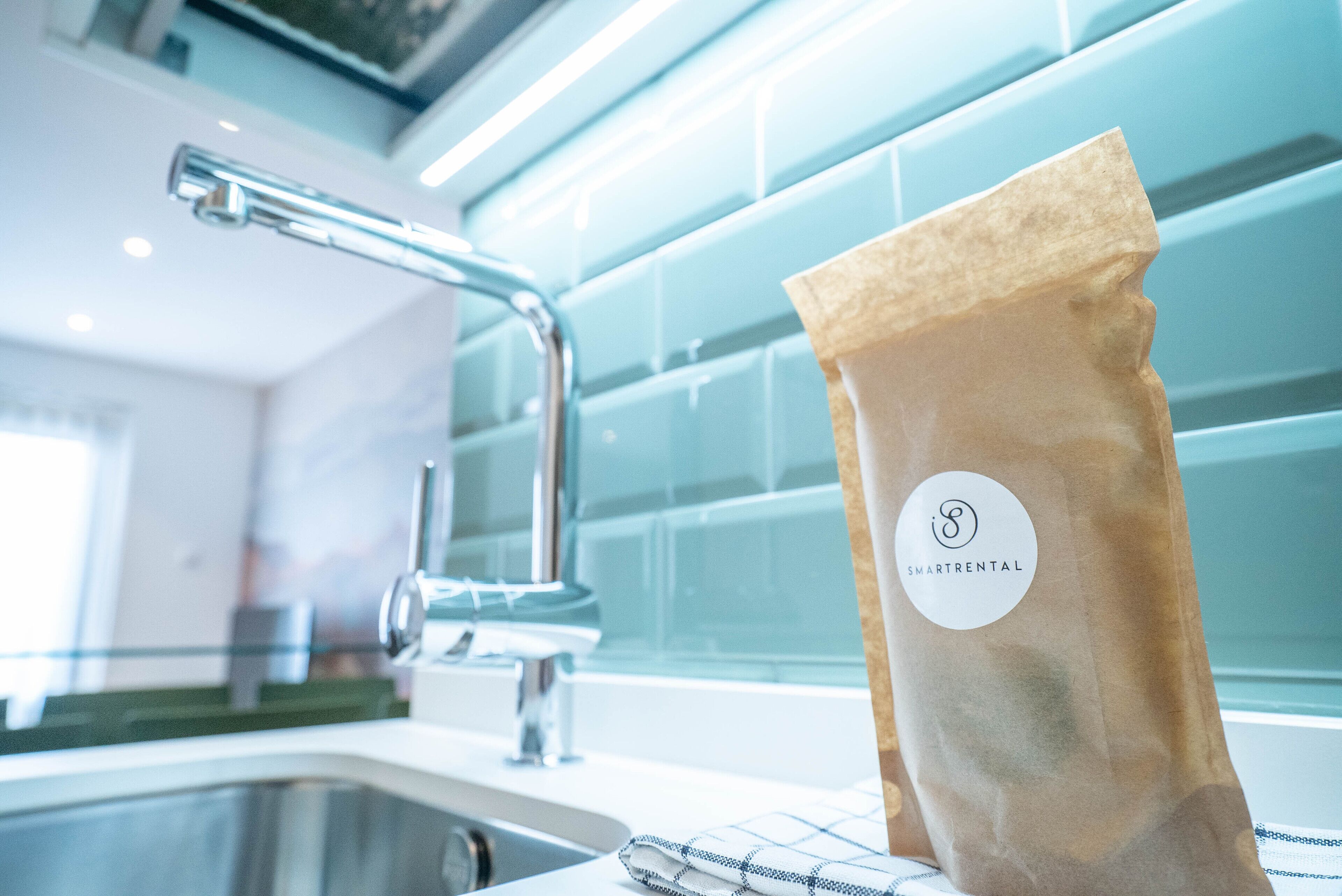 Cozinha moderna com pia de aço inoxidável, uma torneira e um saco de papel com logotipo.
