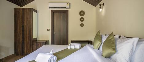 Quarto de hotel com cama grande, guarda-roupa de madeira, unidade de ar condicionado, espelho e luminária na parede.