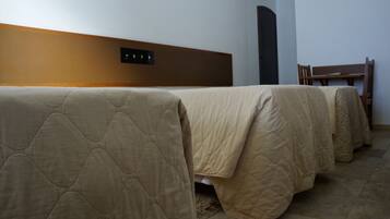 Quarto de hotel com uma cama, mesa de cabeceira e uma cadeira.