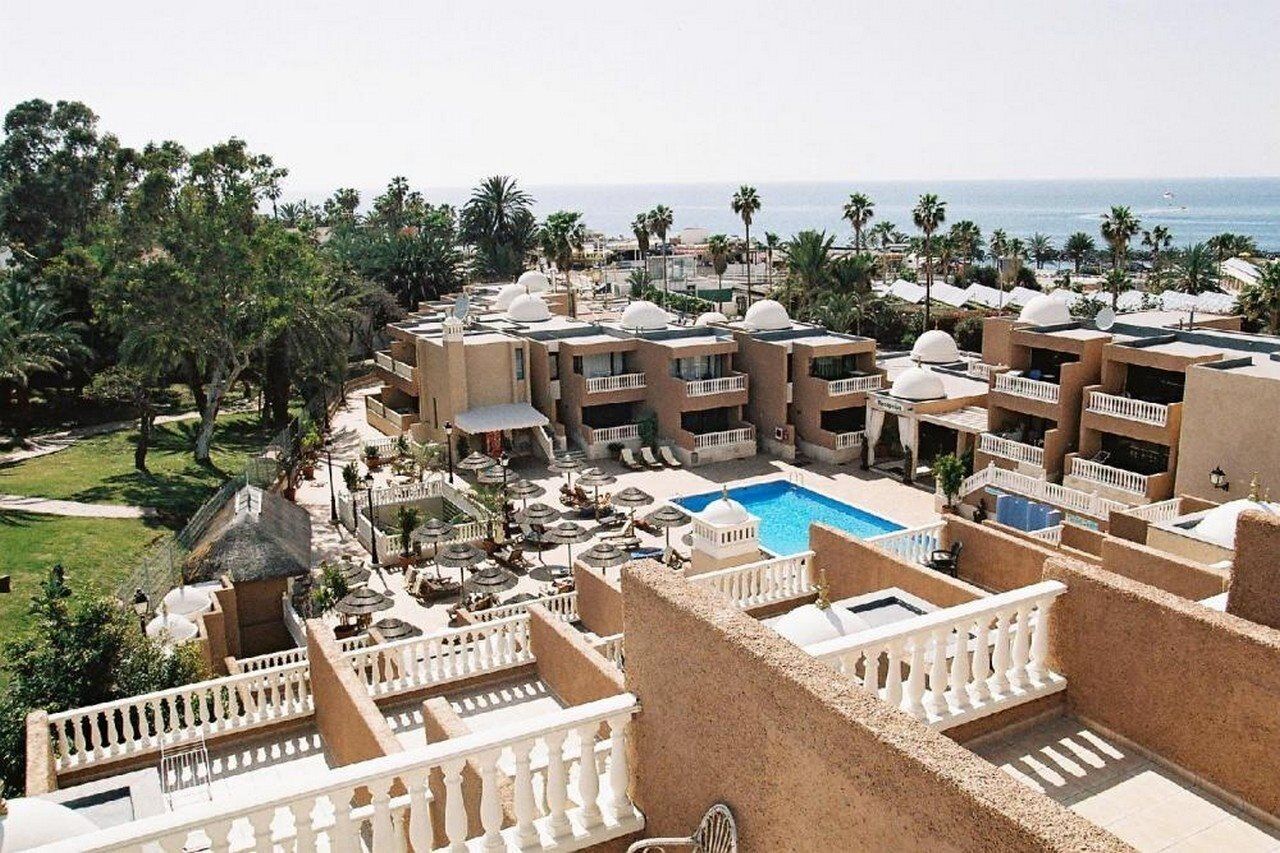Um resort com vários edifícios, piscina e vista para o mar.