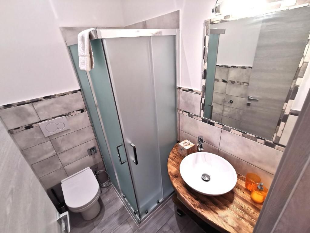 Um banheiro moderno com box de vidro, toucador de madeira com pia e vaso sanitário.