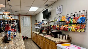 Espaço de bar com café, máquinas de snack, micro-ondas e frigorífico.
