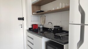 Uma cozinha compacta com micro-ondas, cafeteira e uma pia pequena.