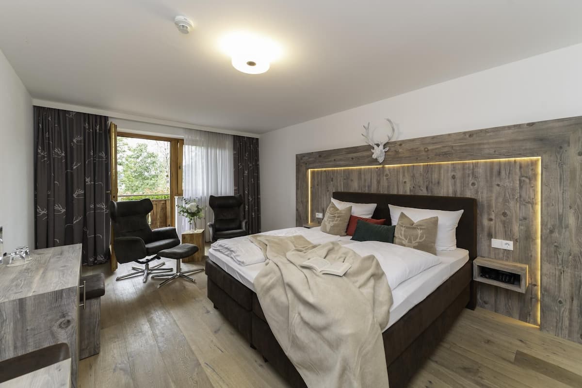 Quarto moderno com uma cama grande, cabeceira de madeira e uma escrivaninha com cadeira.