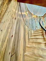 Uma escada de madeira com design curvo, luzes de fada e teto branco.