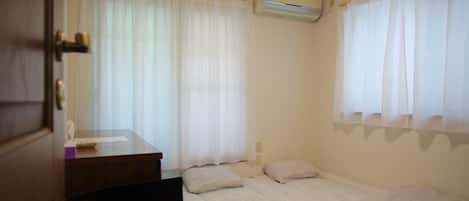 Quarto pequeno e limpo, com duas camas, uma escrivaninha e ar condicionado.