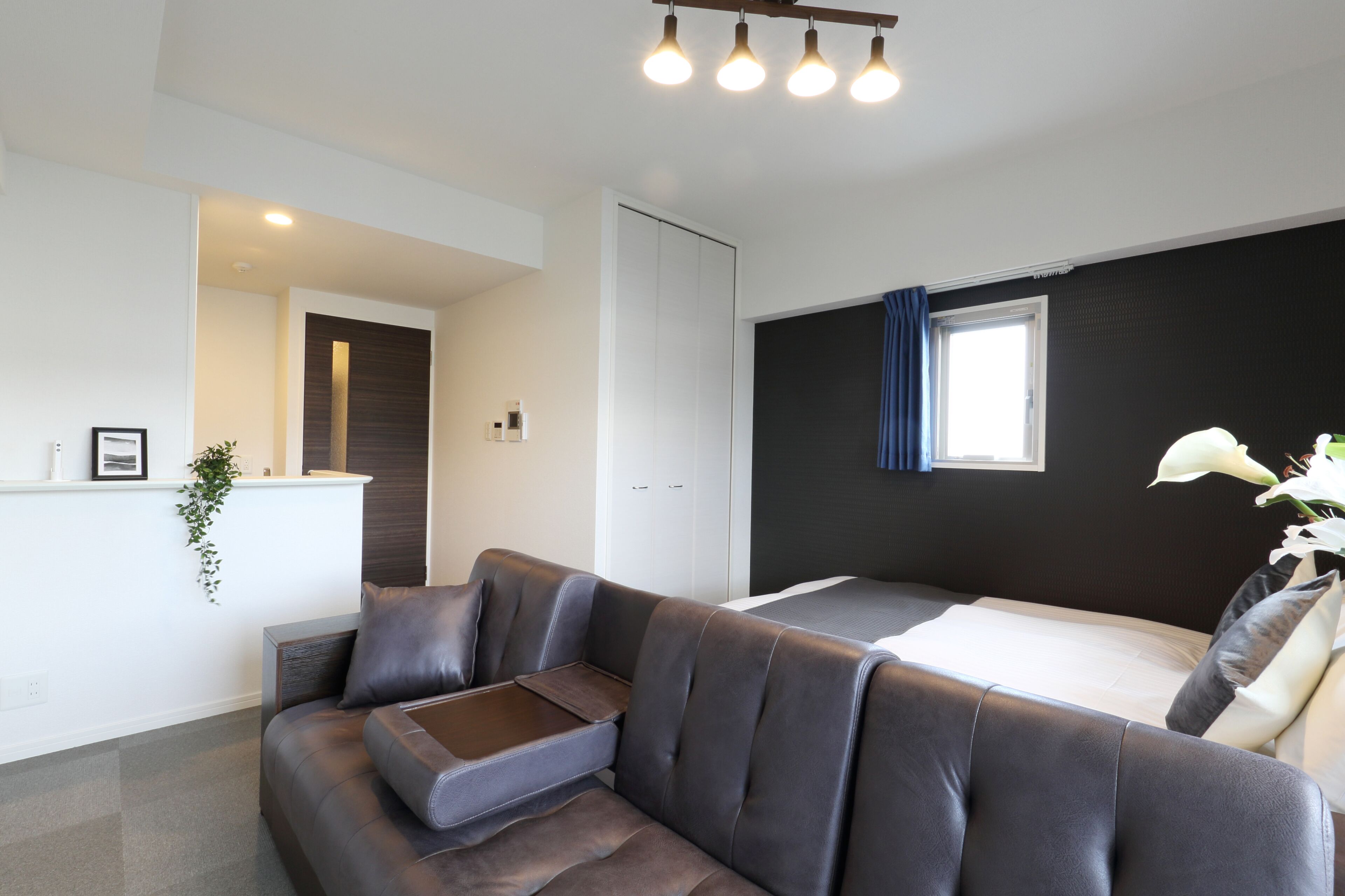Quarto moderno com sofá de cor escura, uma cama e um pequeno espaço de trabalho.