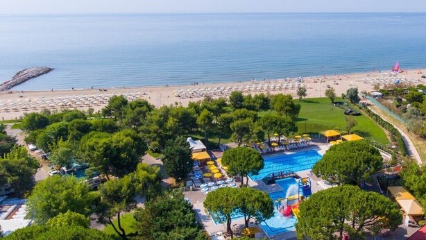 Um resort com uma grande área de piscina, uma praia e uma torre de salva-vidas.