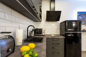 Uma cozinha moderna com geladeira preta, eletrodomésticos de aço inoxidável e painel de azulejos.