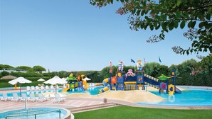 Uma área de piscina com estrutura de recreação aquática, cadeiras de lounge e uma pequena banheira de hidromassagem.