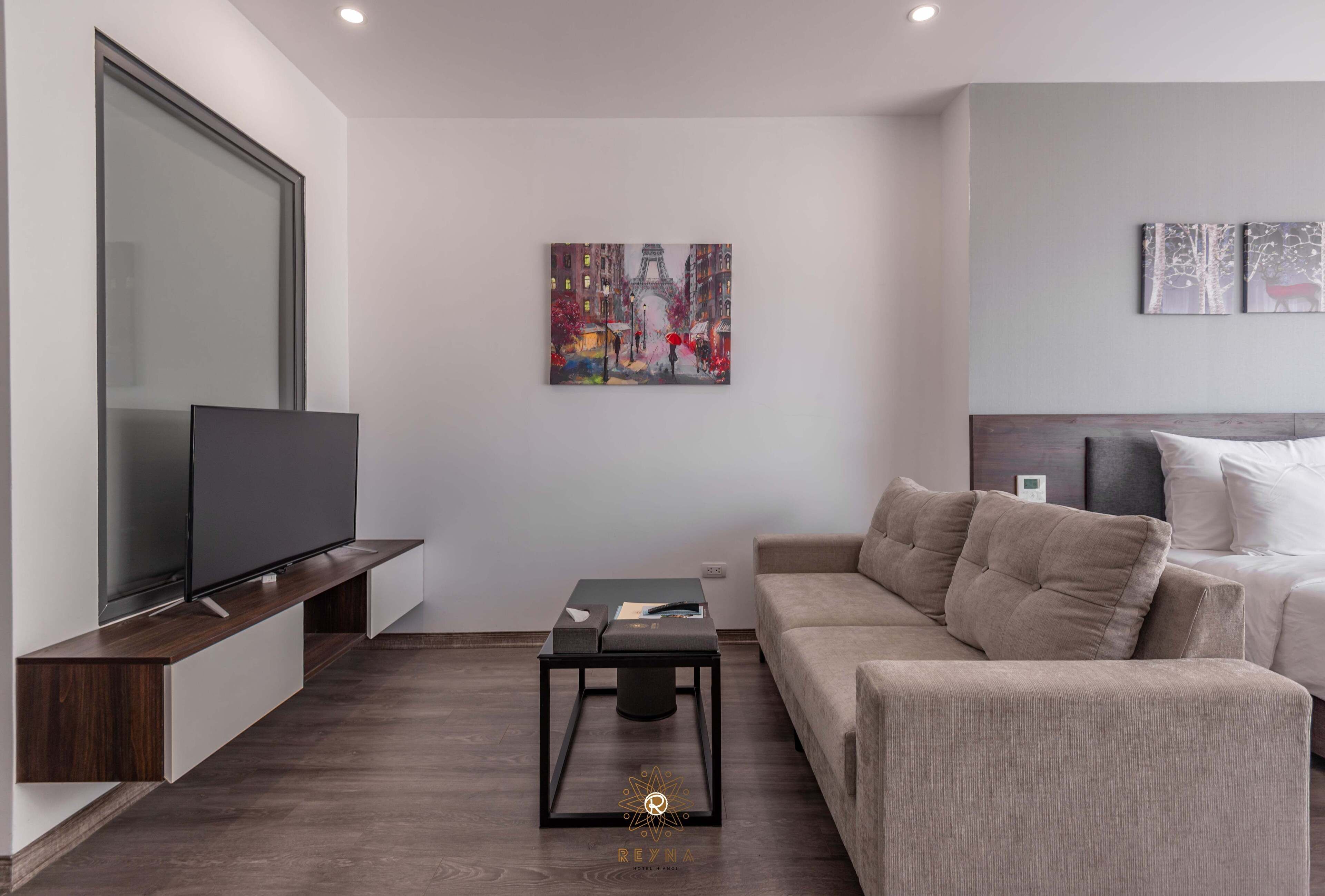 Uma sala de estar moderna com uma TV de tela plana, um sofá, uma mesa de centro e obras de arte nas paredes.