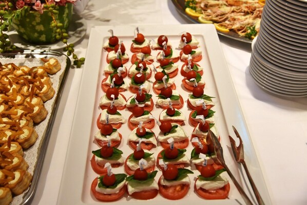 Buffet com diversos pratos, incluindo petiscos e uma salada.
