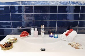 Casa de banho com uma pia branca, um espelho e uma parede revestida de azulejos azuis.