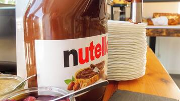Um pote de Nutella com uma colher, uma tigela de cerejas e um pequeno prato com Nutella sobre uma lousa.