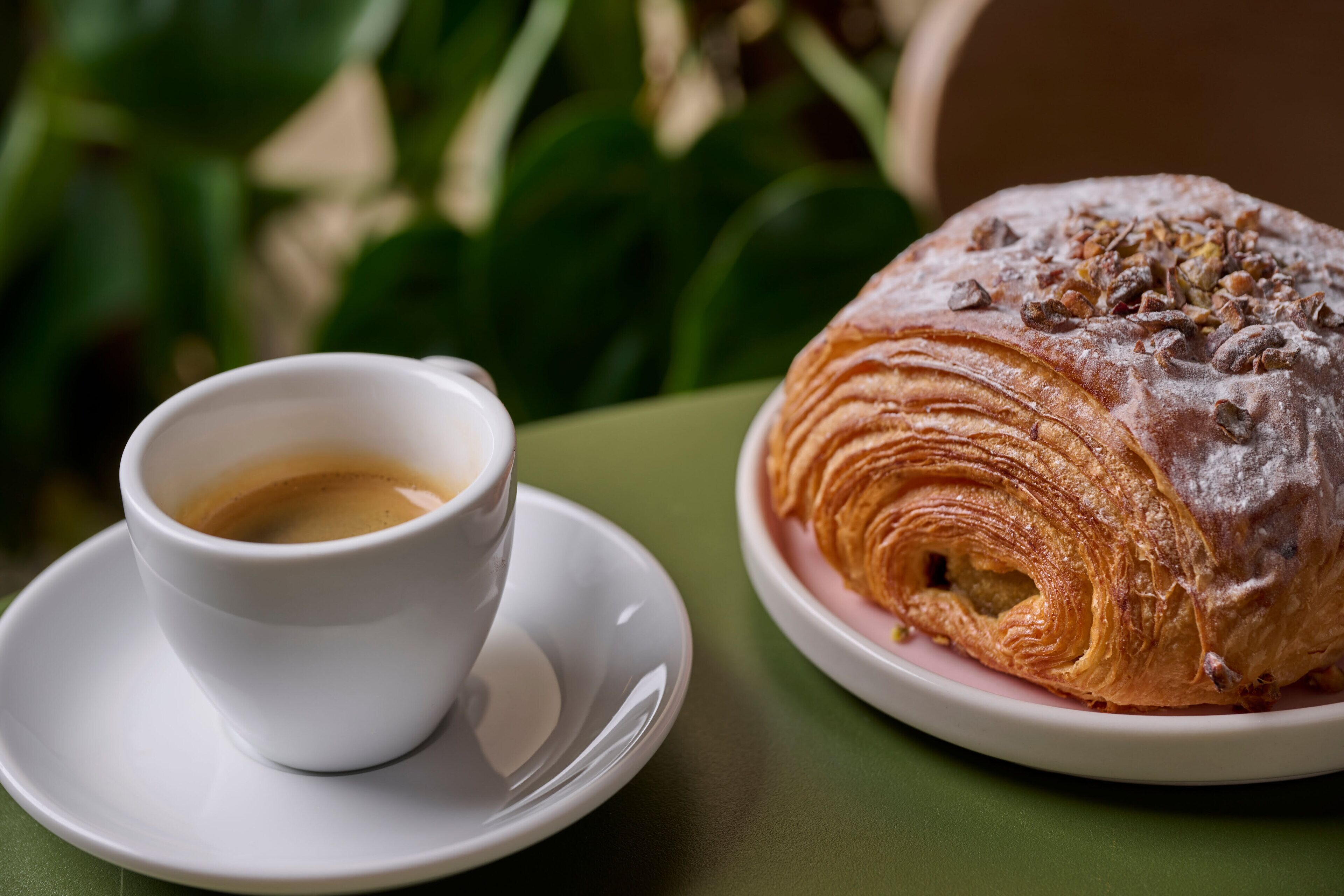 Uma chávena de café e um pastel sobre a mesa.