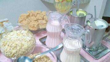 Uma mesa de buffet com diversos alimentos, incluindo cereais, iogurte e ponche de frutas.