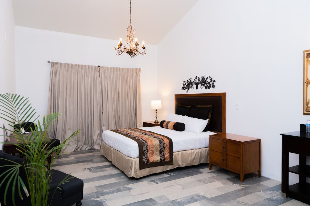 Quarto bem arrumado com cama, mesa de cabeceira, abajur e um objeto decorativo na parede.