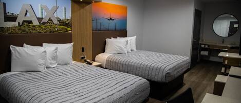 Quarto de hotel com duas camas, uma pintura grande de um avião e vista para a paisagem urbana.