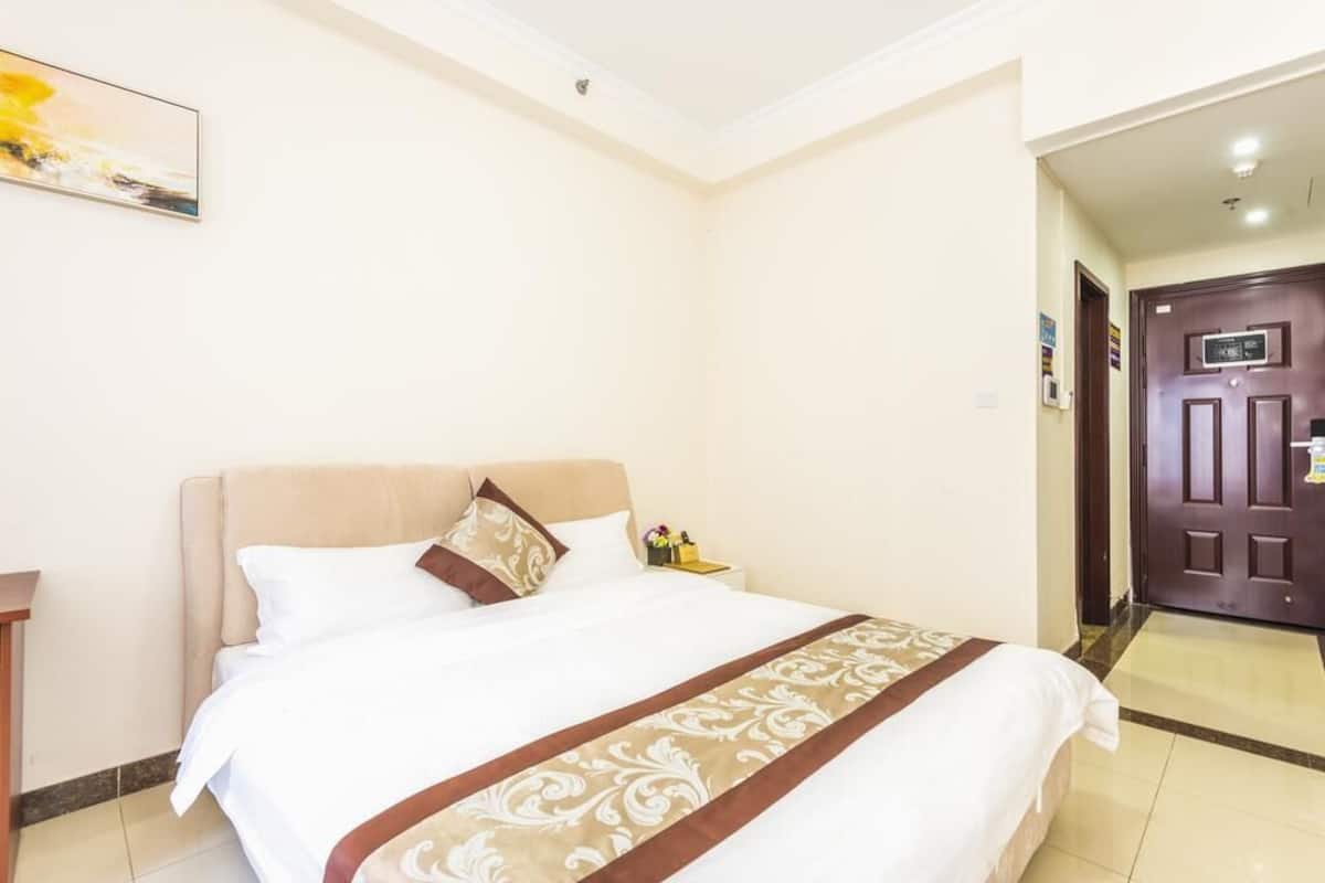 Quarto de hotel com uma cama, uma mesa de cabeceira e uma porta.