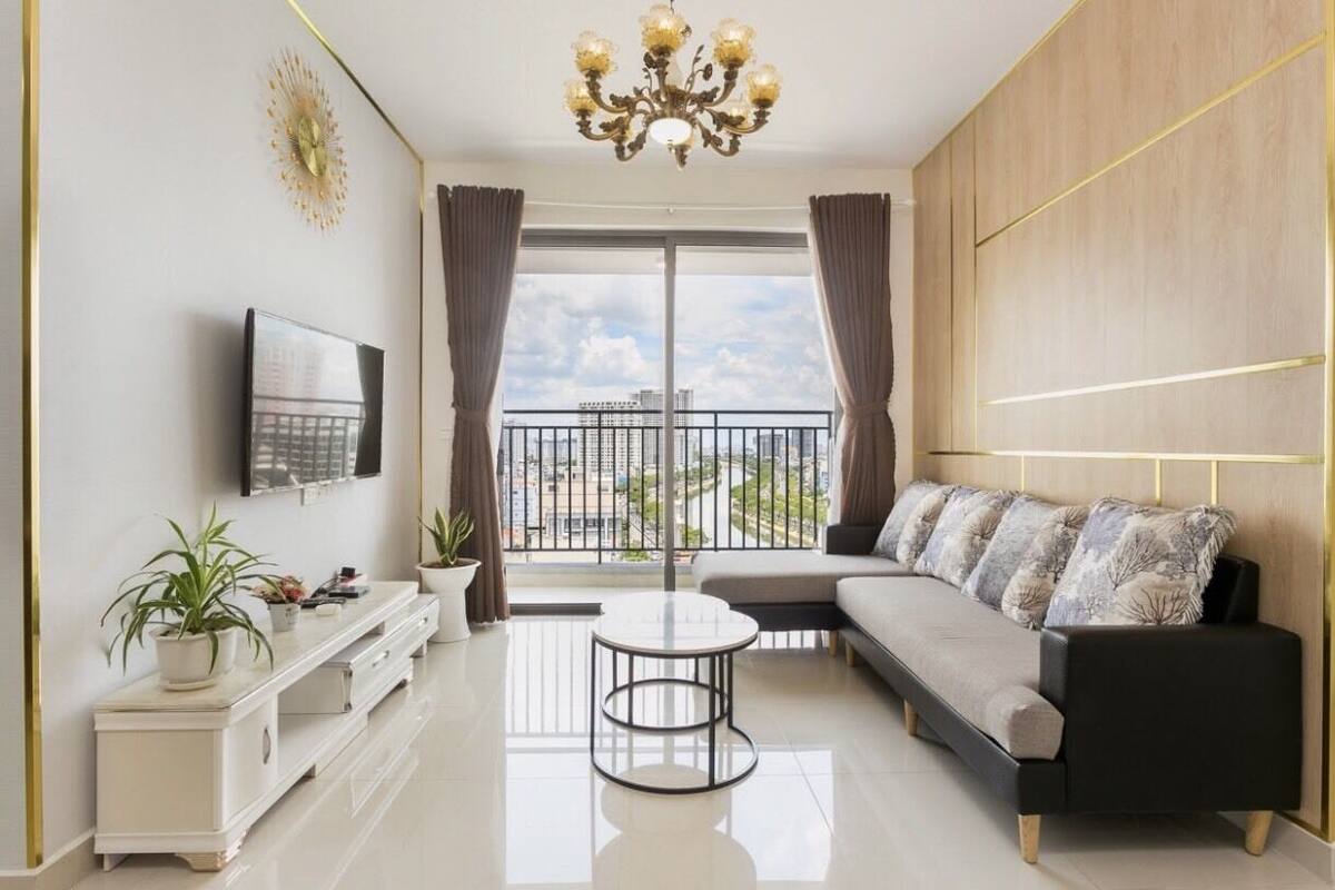 Uma sala de estar moderna com sofá, televisão, lustre e varanda com vista.