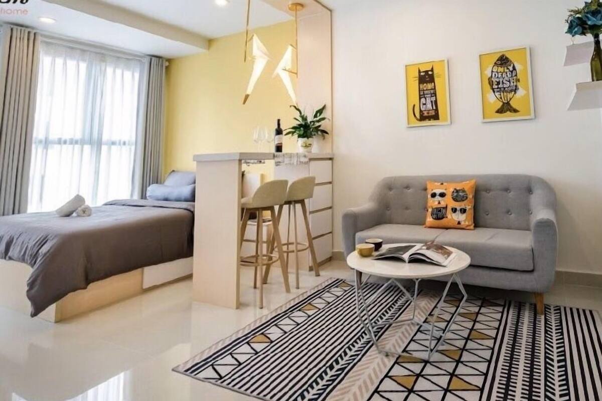 Uma sala de estar moderna com sofá, mesa de centro e área de jantar com cadeiras e um pequeno balcão de cozinha.