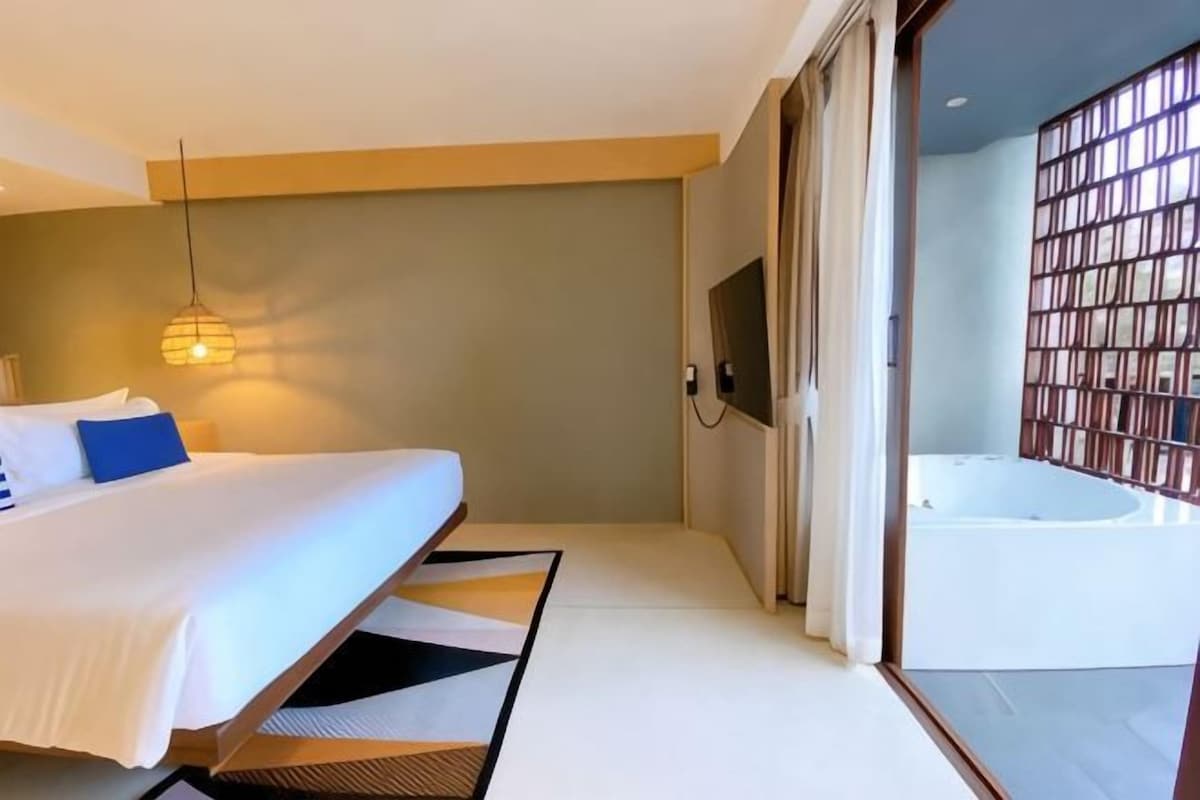 Quarto com cama, televisão, janela e banheiro com banheira.