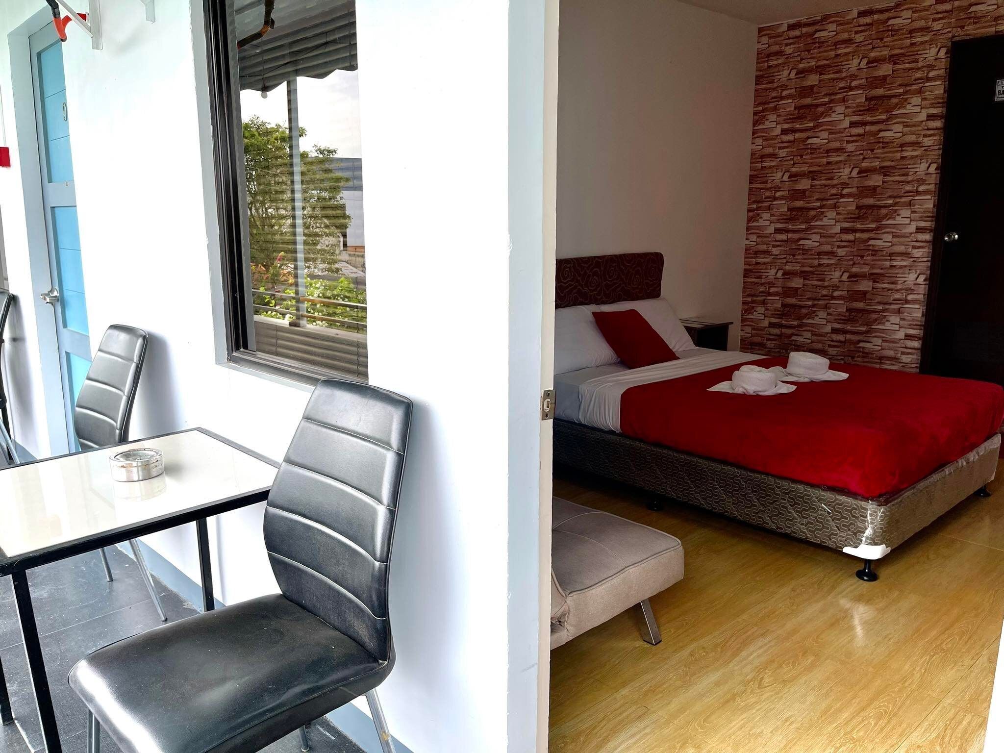 Quarto de hotel com uma cama, uma escrivaninha e uma cadeira.