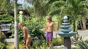 Um jardim com uma fonte, palmeiras e um caminho.