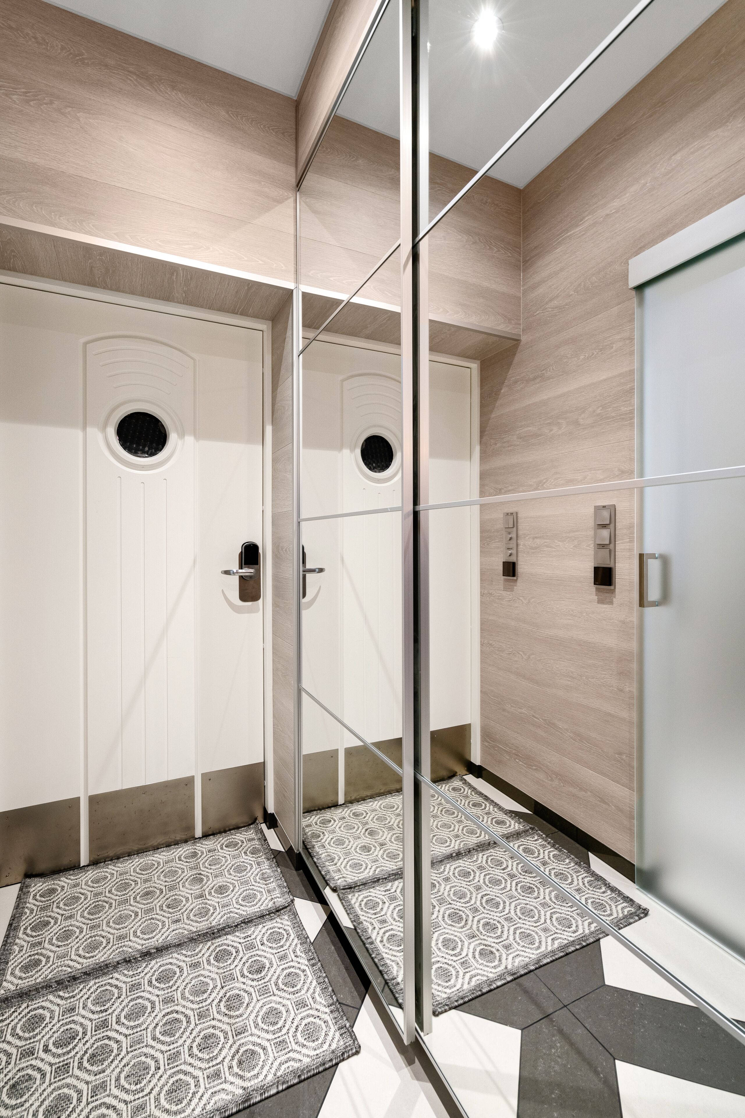 Um elevador moderno com paredes espelhadas e tapetes de chão estampados.
