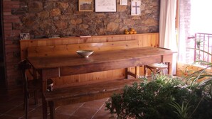 Paredes de pedra rústicas com um banco e mesa de madeira, um candeeiro pendente e uma moldura com imagem.