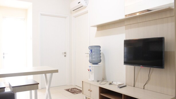Uma sala de estar moderna com uma TV de tela plana fixada em uma parede de madeira, um bebedouro e um pequeno armário embaixo.