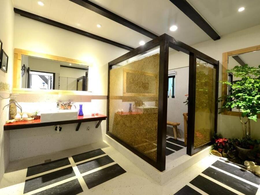 Uma casa de banho moderna com um espelho grande, duas pias e uma planta em vaso.