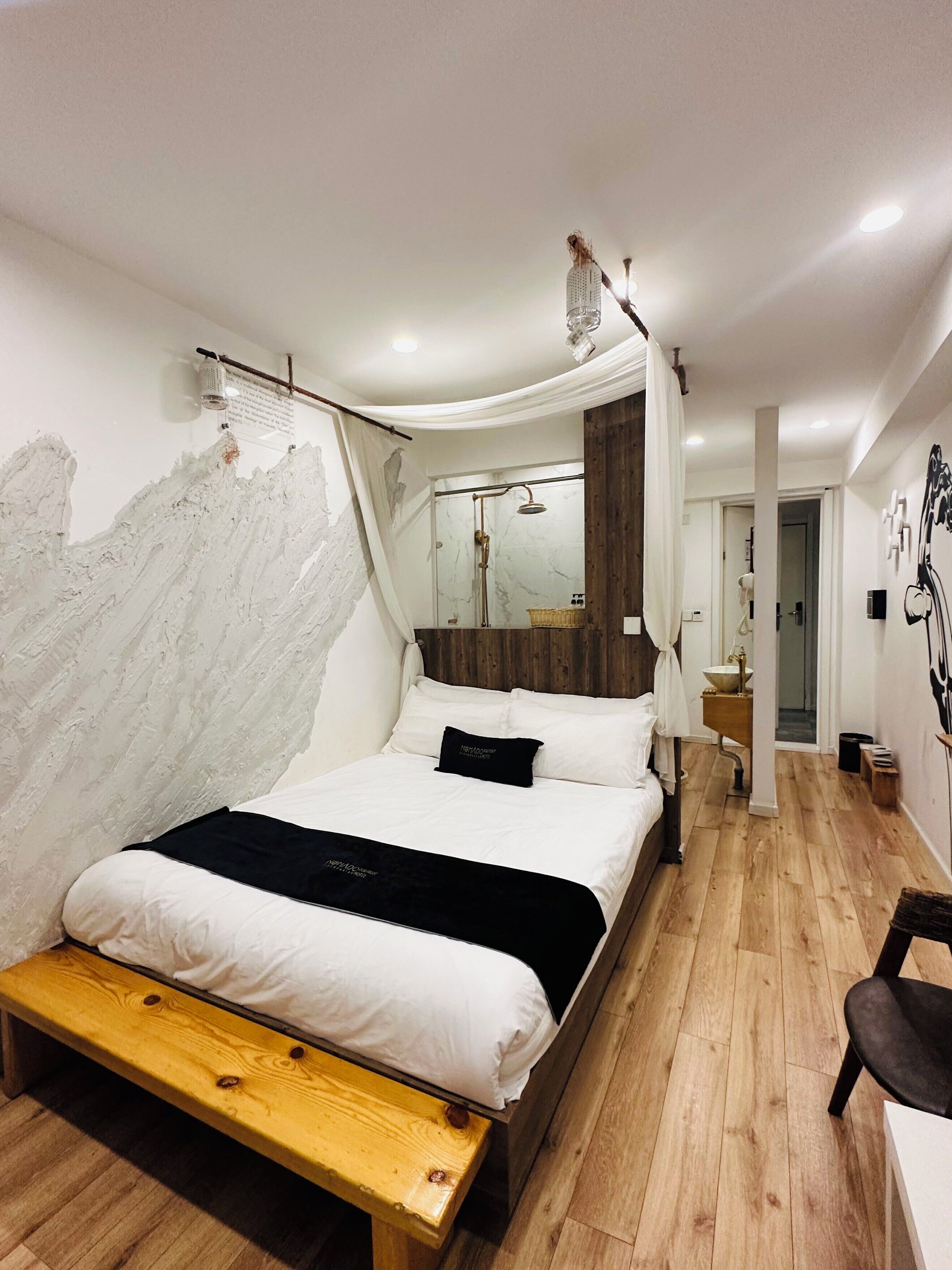 Quarto moderno com cama de madeira, cabeceira branca e chão de madeira.