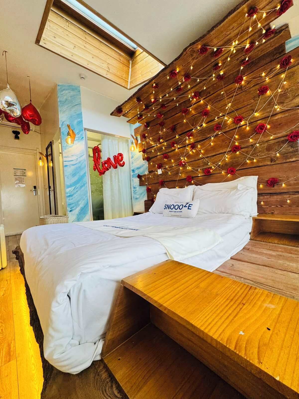Quarto moderno com cabeceira de madeira, cama com roupa de cama branca e luminária decorativa.